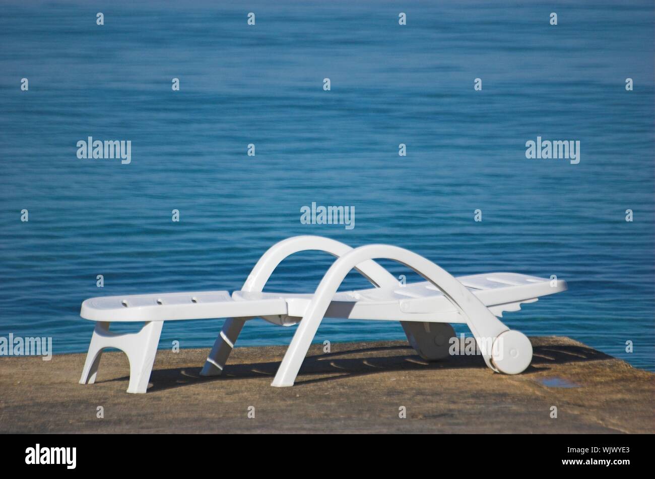 Plastic beach chair at the edge of a sea Stock Photo - Alamy