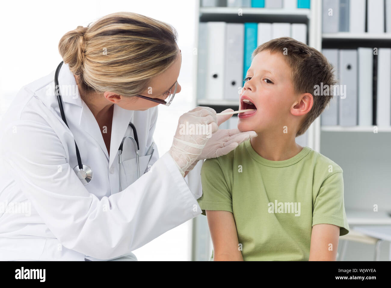 Female doctor checking mouth of boy in clinic Stock Photo - Alamy