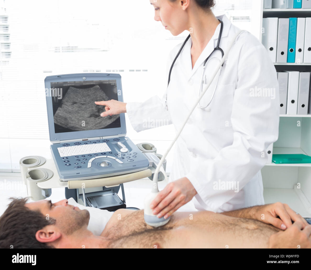 Female cardiologist using sonogram on male patient in examination room ...