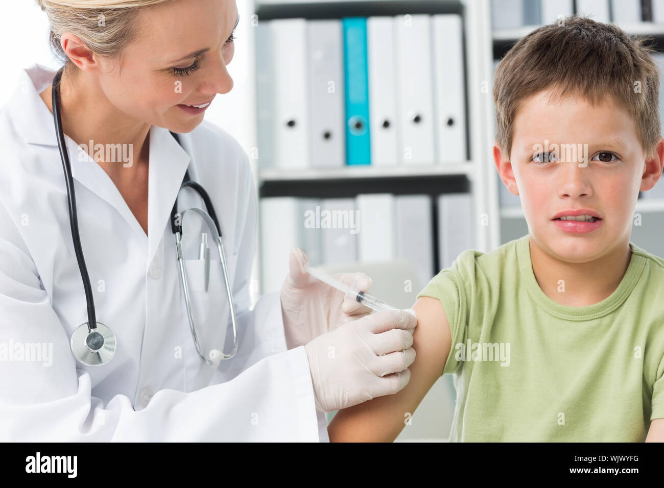 Innocent boy receiving an injection by female pediatrician in clinic ...
