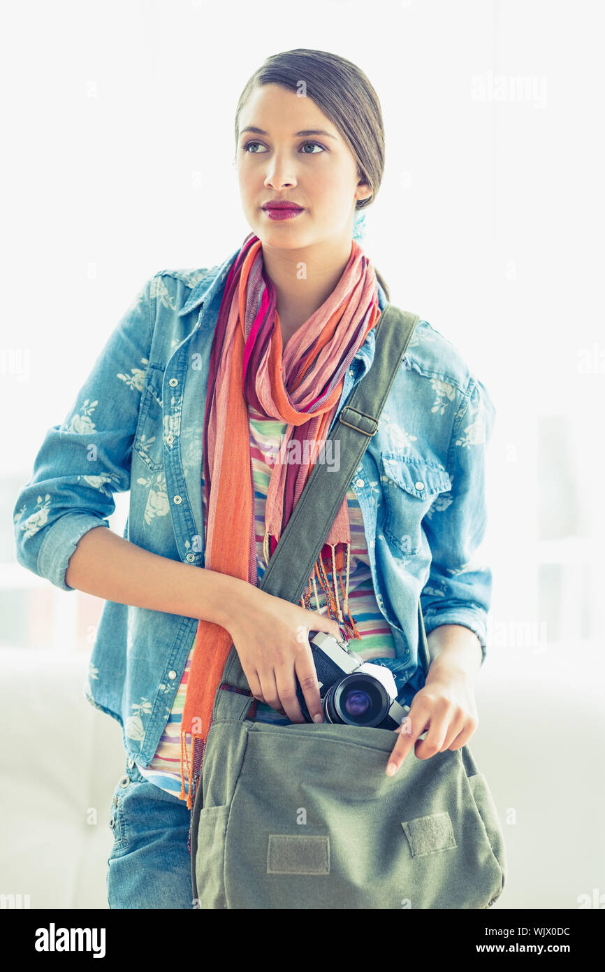 Young thinking woman taking camera from her bag on white background ...
