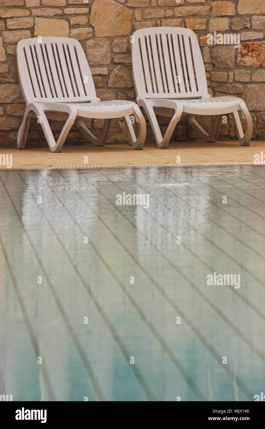 White plastic seats standing on a terrace next to a pool Stock Photo ...
