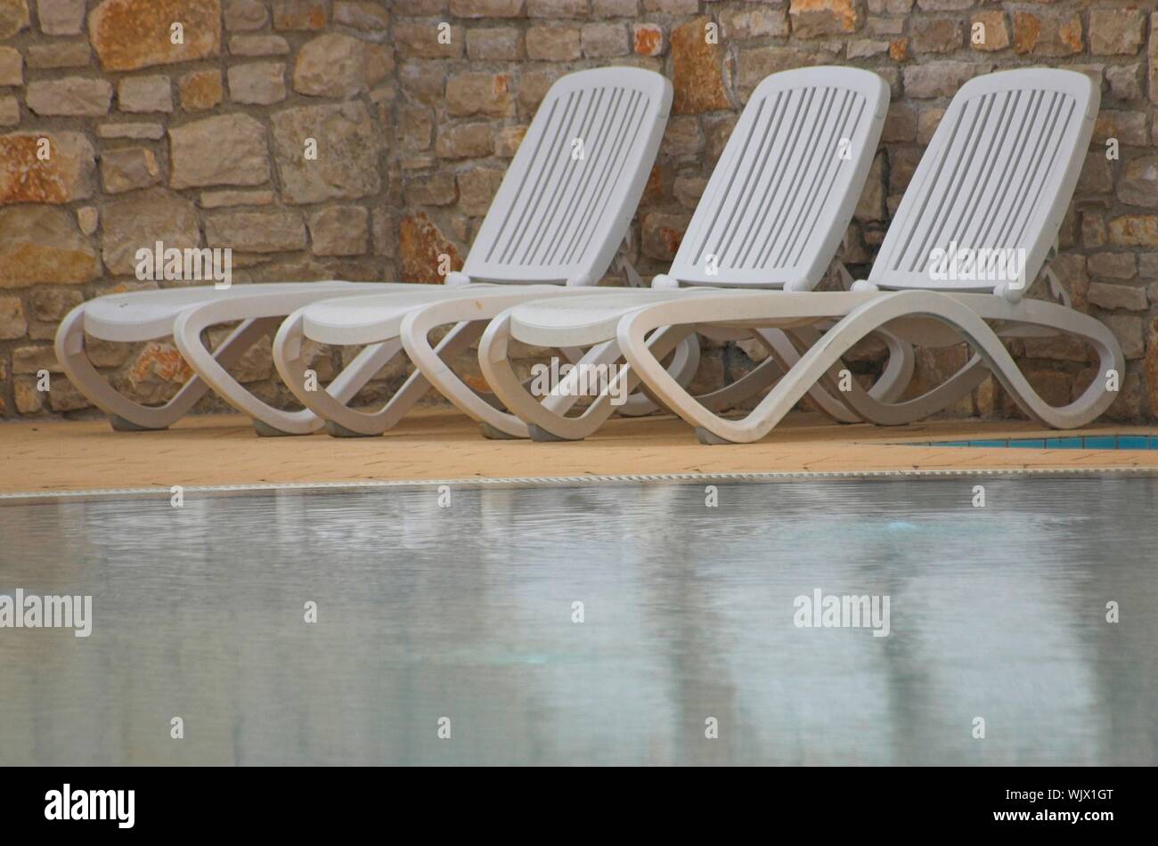 White plastic seats standing on a terrace next to a pool Stock Photo ...
