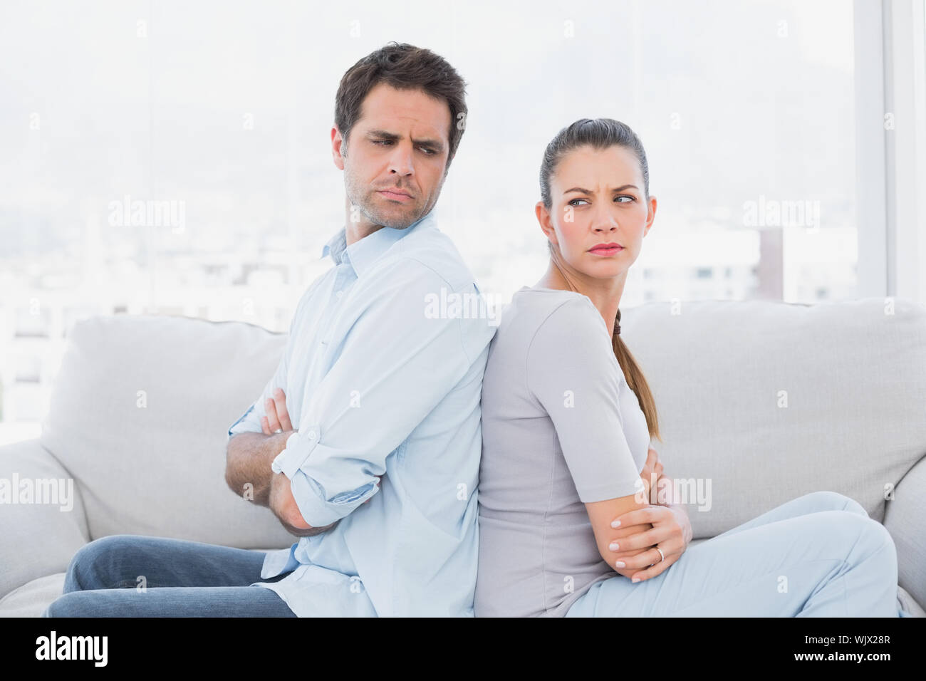 Angry couple sitting back to back on the couch at home in the living ...