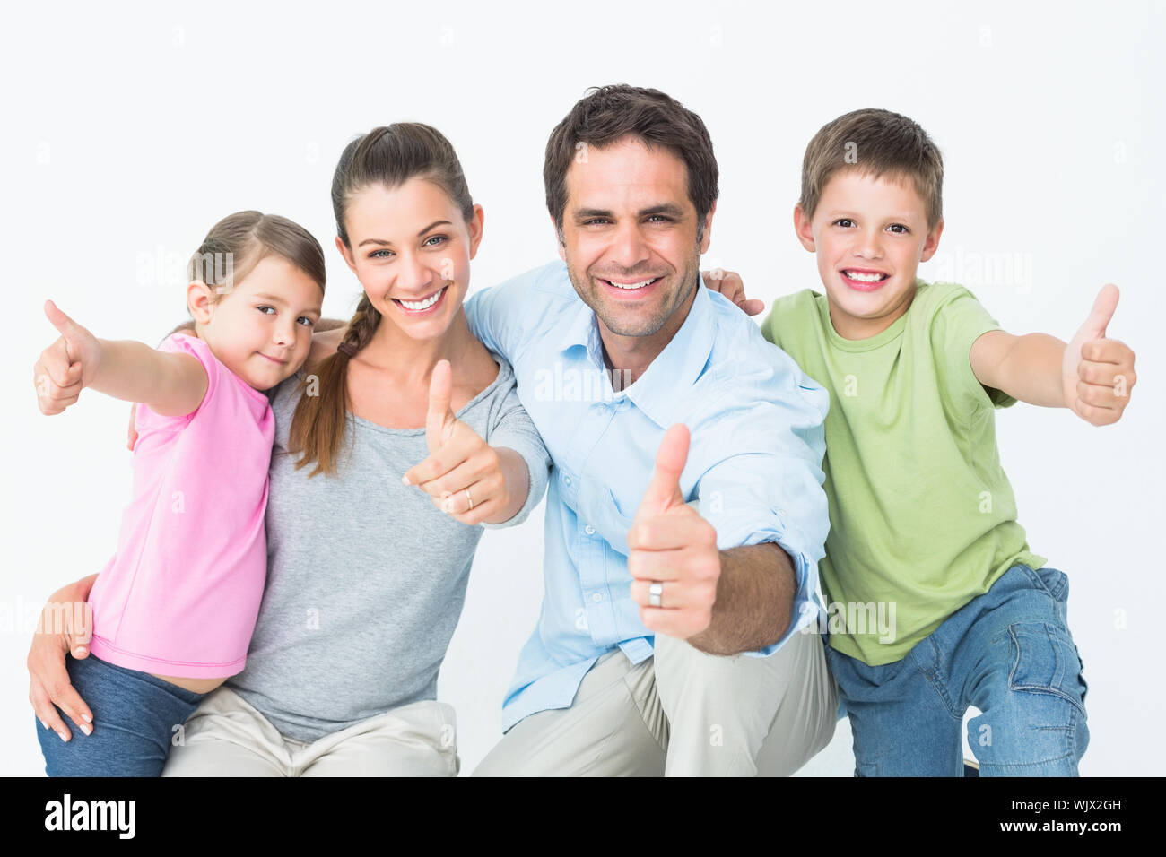 Cute family smiling at camera together showing thumbs up on white ...