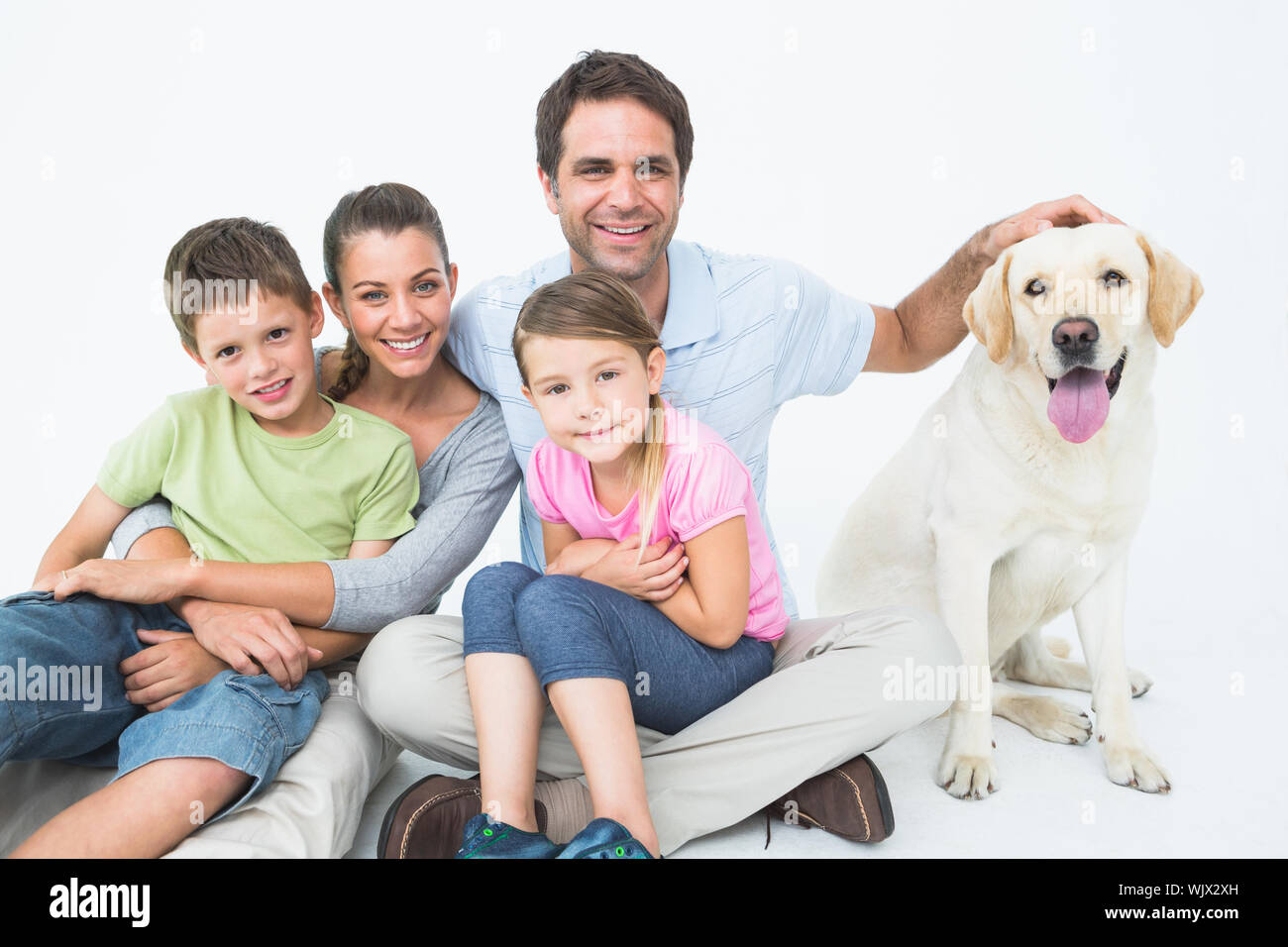 Cute family with pet labrador posing and smiling at camera together on ...