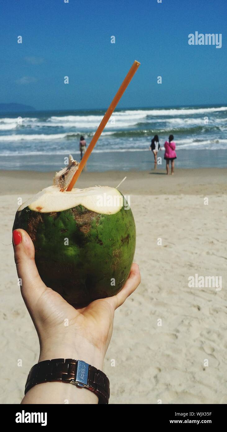Hand holding coconut on beach hi-res stock photography and images - Alamy