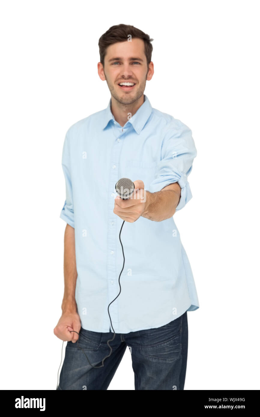 Portrait of a young man holding out microphone over white background ...