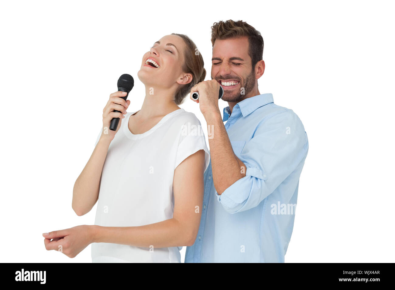 Cheerful couple singing into microphones over white background Stock ...