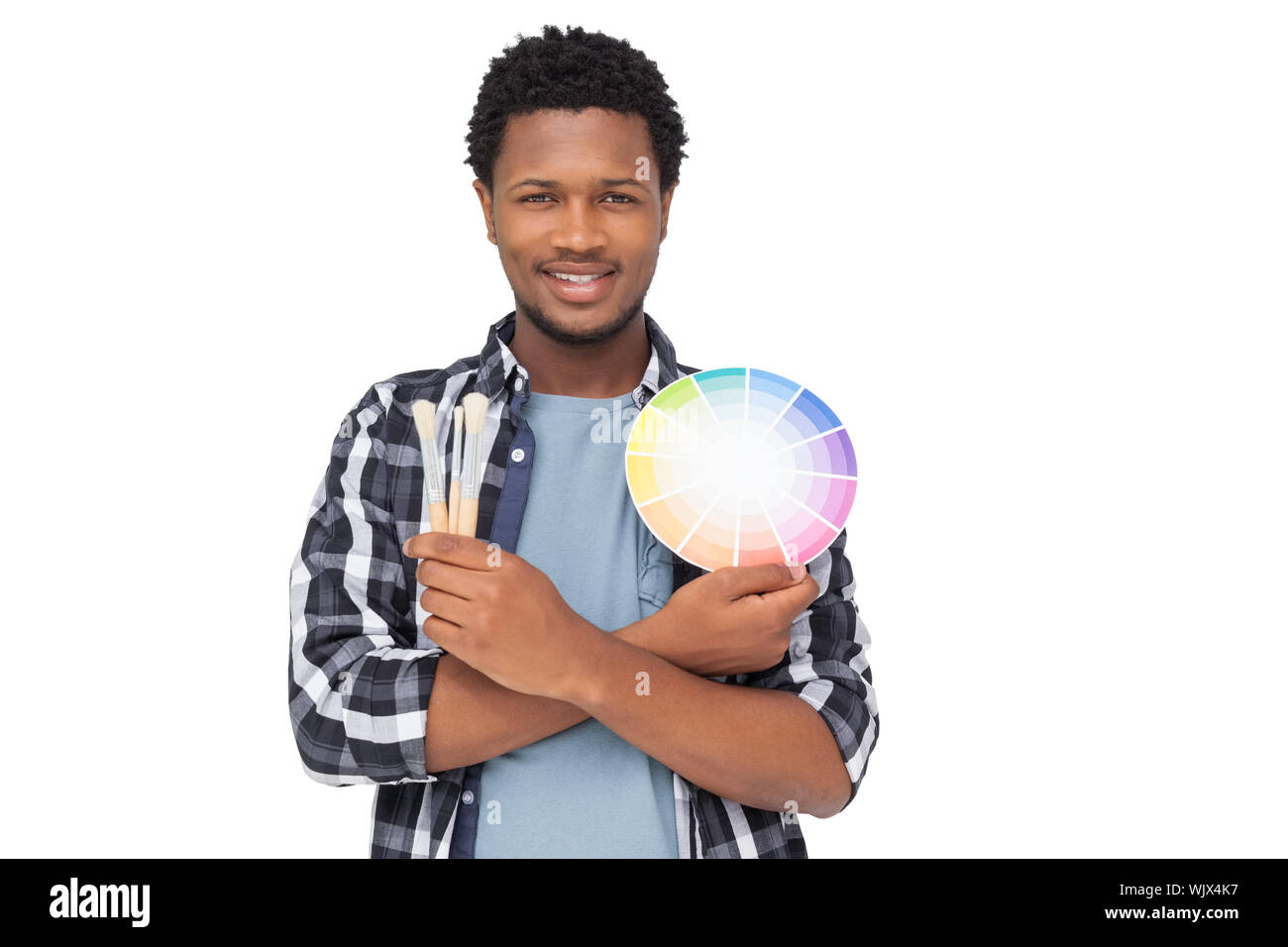 Portrait of a young man with paint sample and paintbrush over white ...