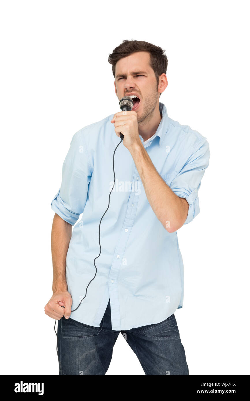 Portrait of a young man singing into microphone over white background Stock Photo - Alamy