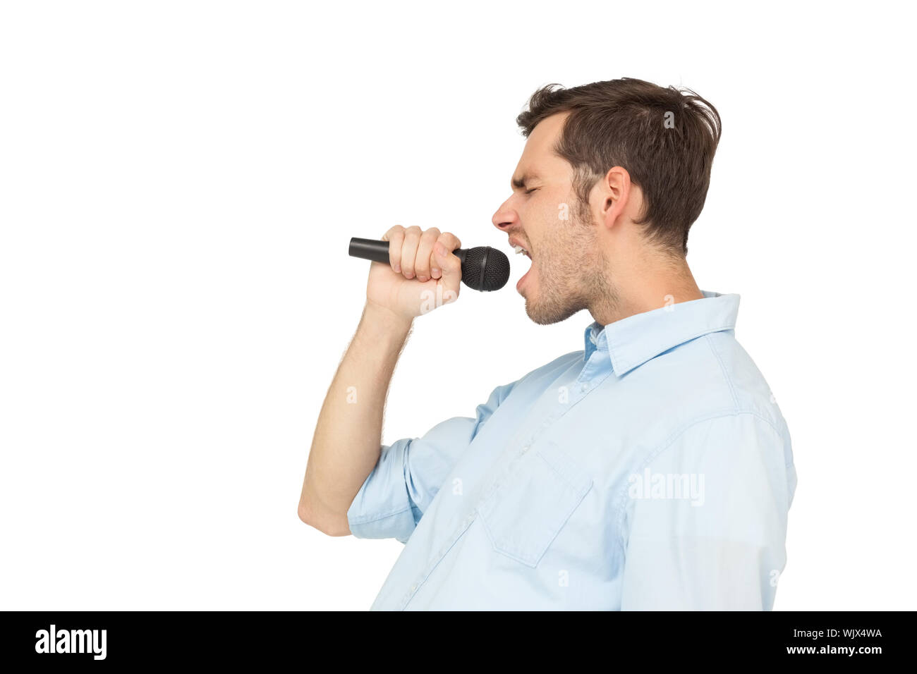 Side view of a young man singing into microphone over white background Stock Photo - Alamy