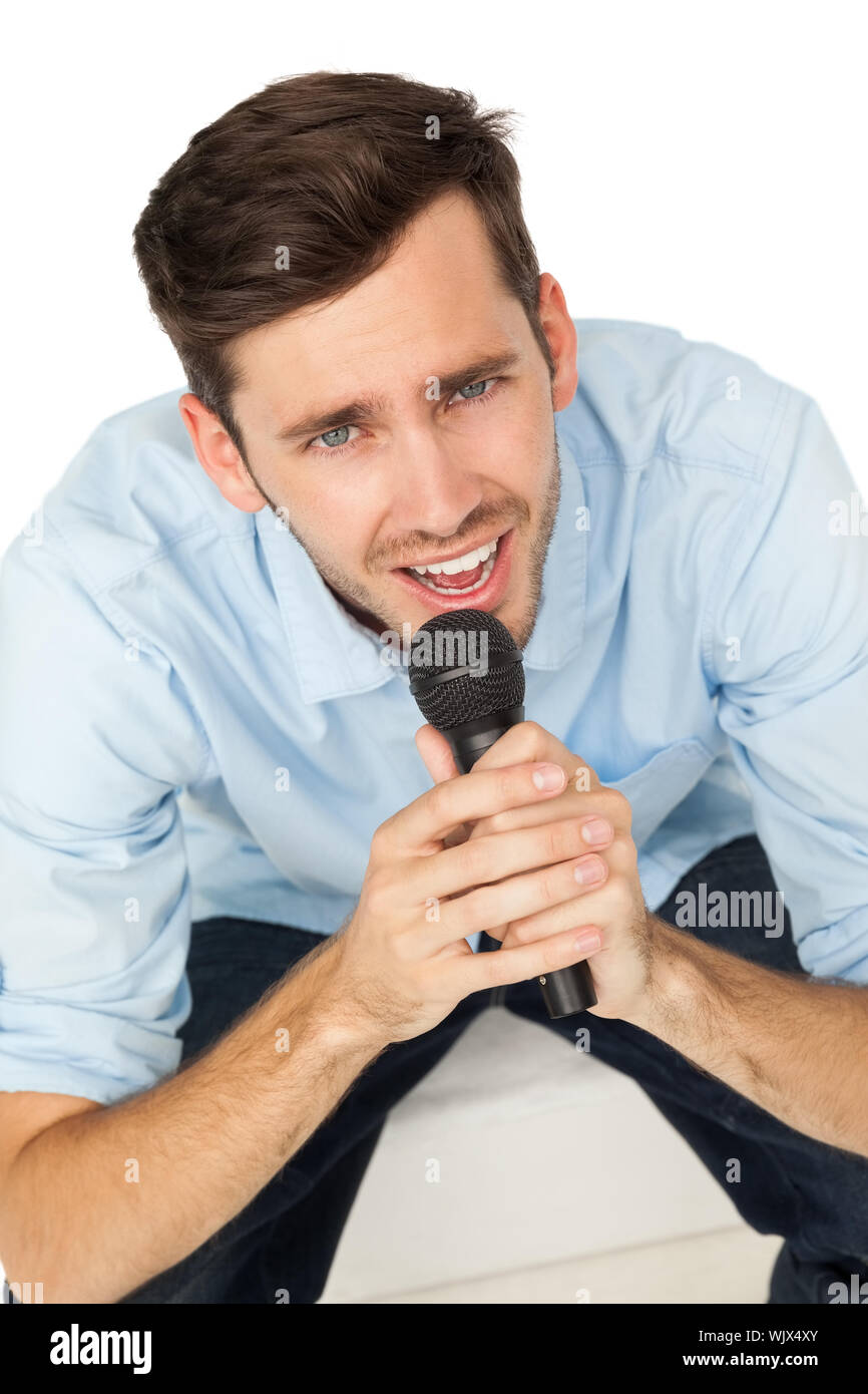 Portrait of a young man singing into microphone over white background Stock Photo - Alamy