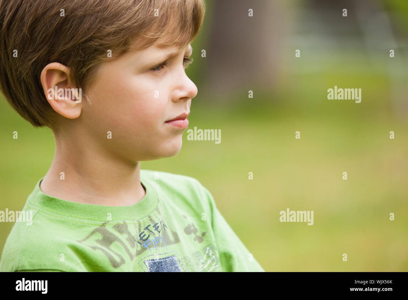 Side view of a serious young boy at the park Stock Photo - Alamy