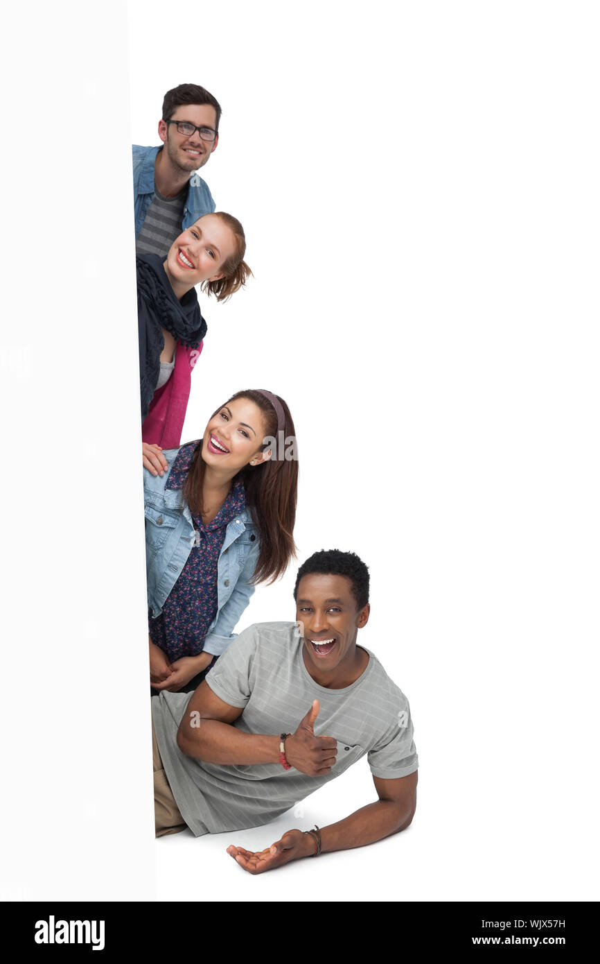 Portrait of four happy young friends with blank board over white ...