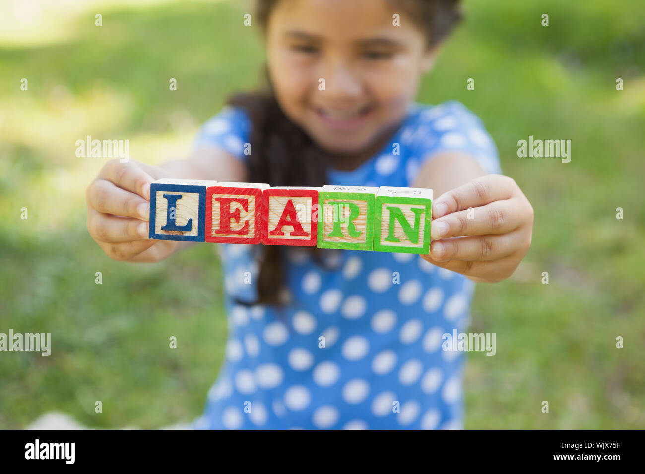 Close-up portrait of a happy young girl holding block alphabets as ...