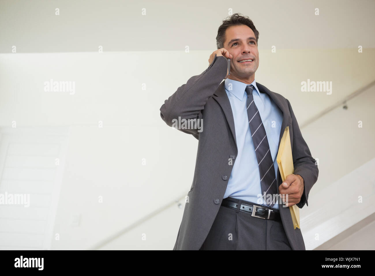 Low angle view of a smiling businessman using cellphone in office Stock ...