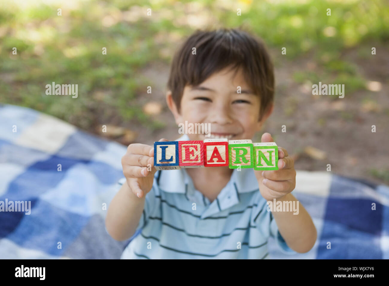 High angle portrait of a happy young boy holding block alphabets as ...