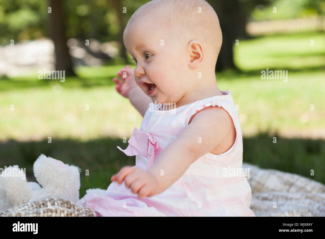 Side view of a cute baby sitting on blanket at the park Stock Photo - Alamy