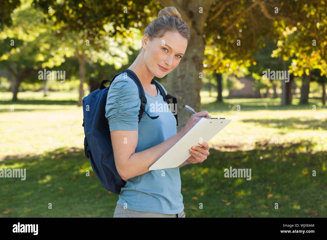 Side view portrait of a beautiful young woman writing on clipboard at ...
