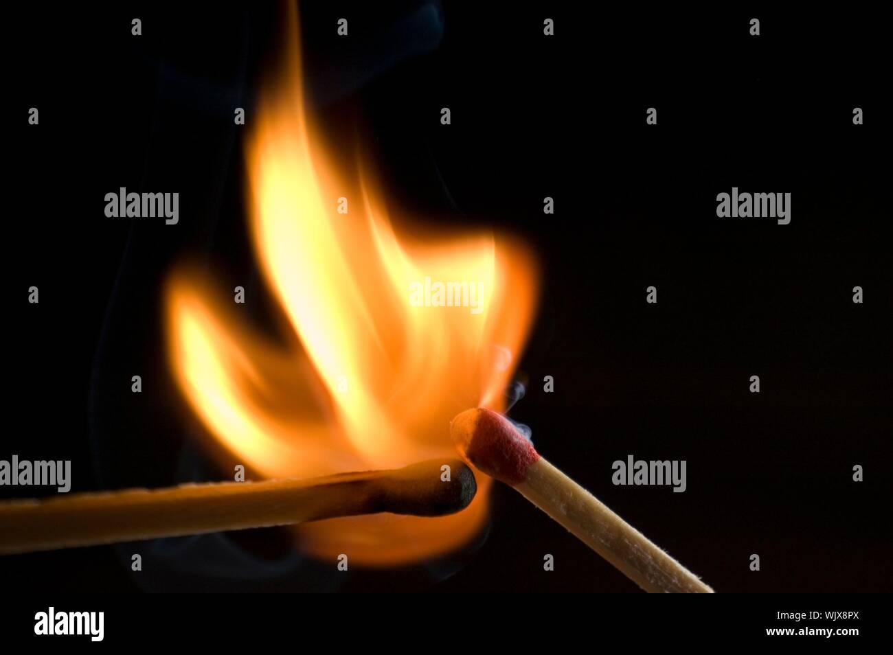 two matches on fire isolated on black background Stock Photo - Alamy