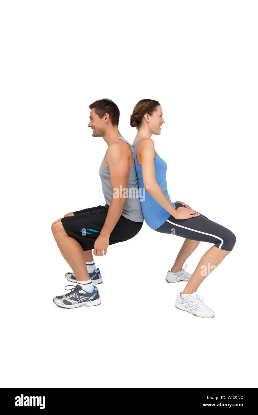 Side view of a fit young couple doing squats over white background ...