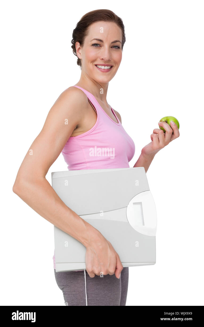 Side view portrait of a young woman with weight scale and apple over ...