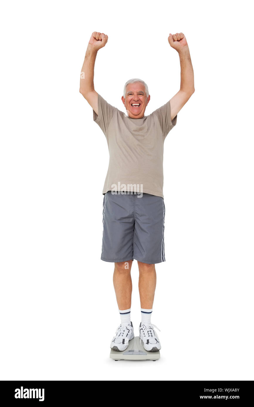 Full length portrait of a senior man cheering on weight scale over ...