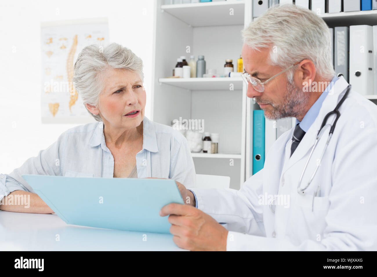 Male doctor with female patient reading reports at medical office Stock ...