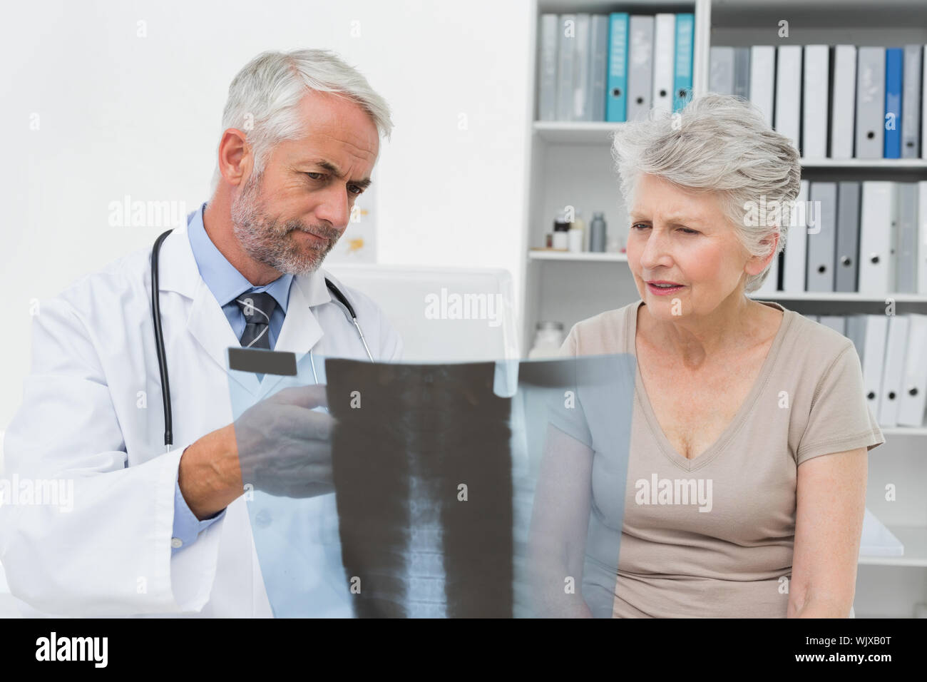 Male doctor explaining x-ray to senior patient in the medical office ...