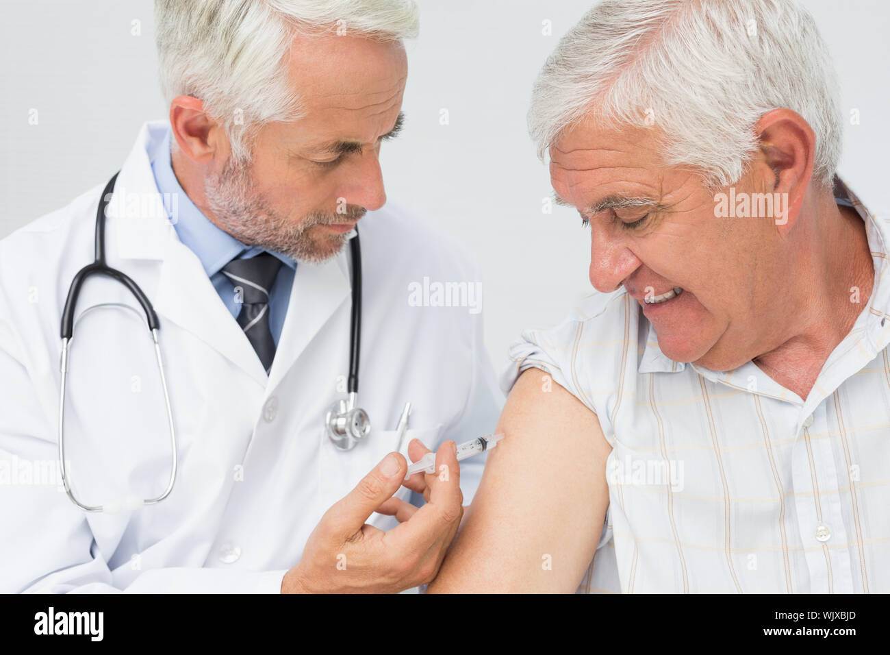 Doctor injecting senior male patient at the medical office Stock Photo ...