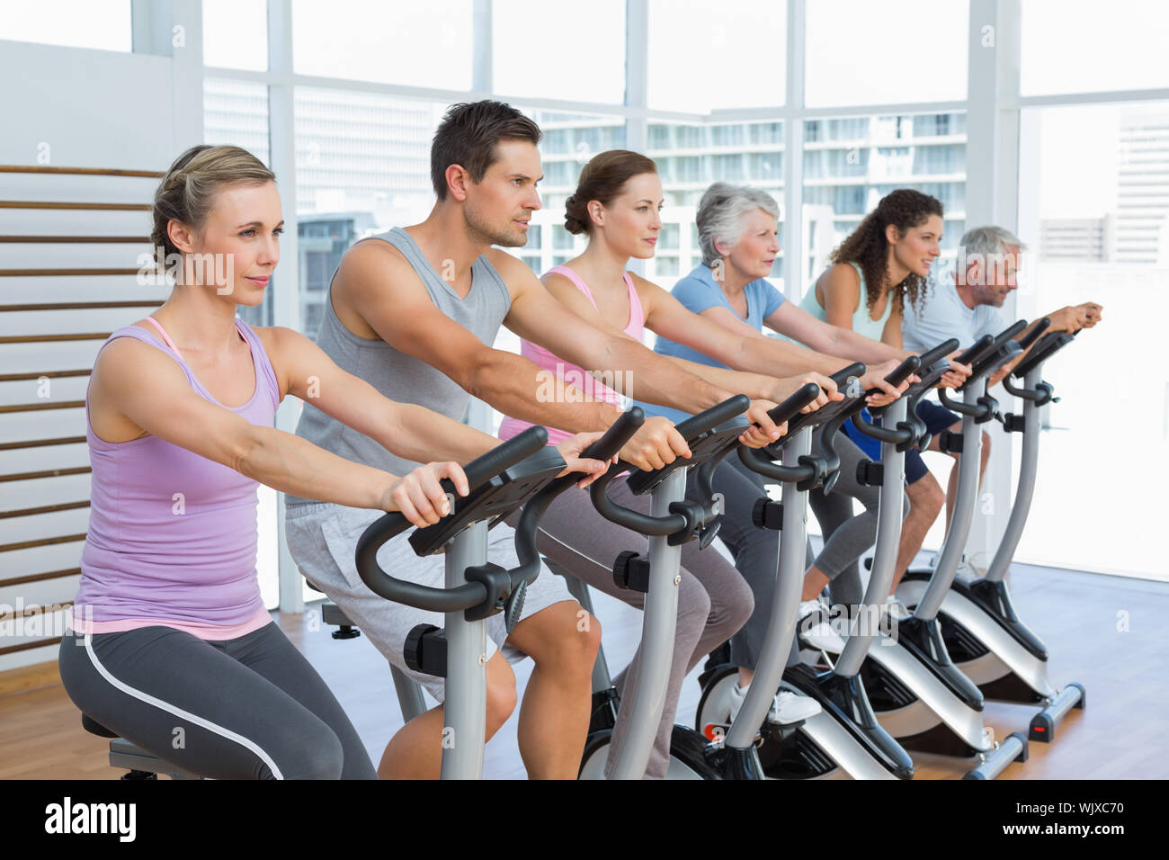 Side view of determined people working out at spinning class in gym ...