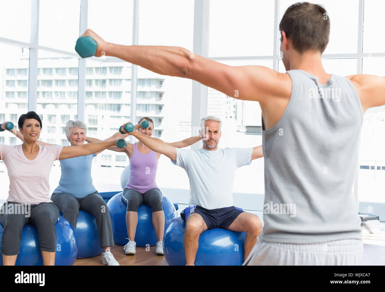 Portrait of fitness class with dumbbells sitting on exercise balls in a ...