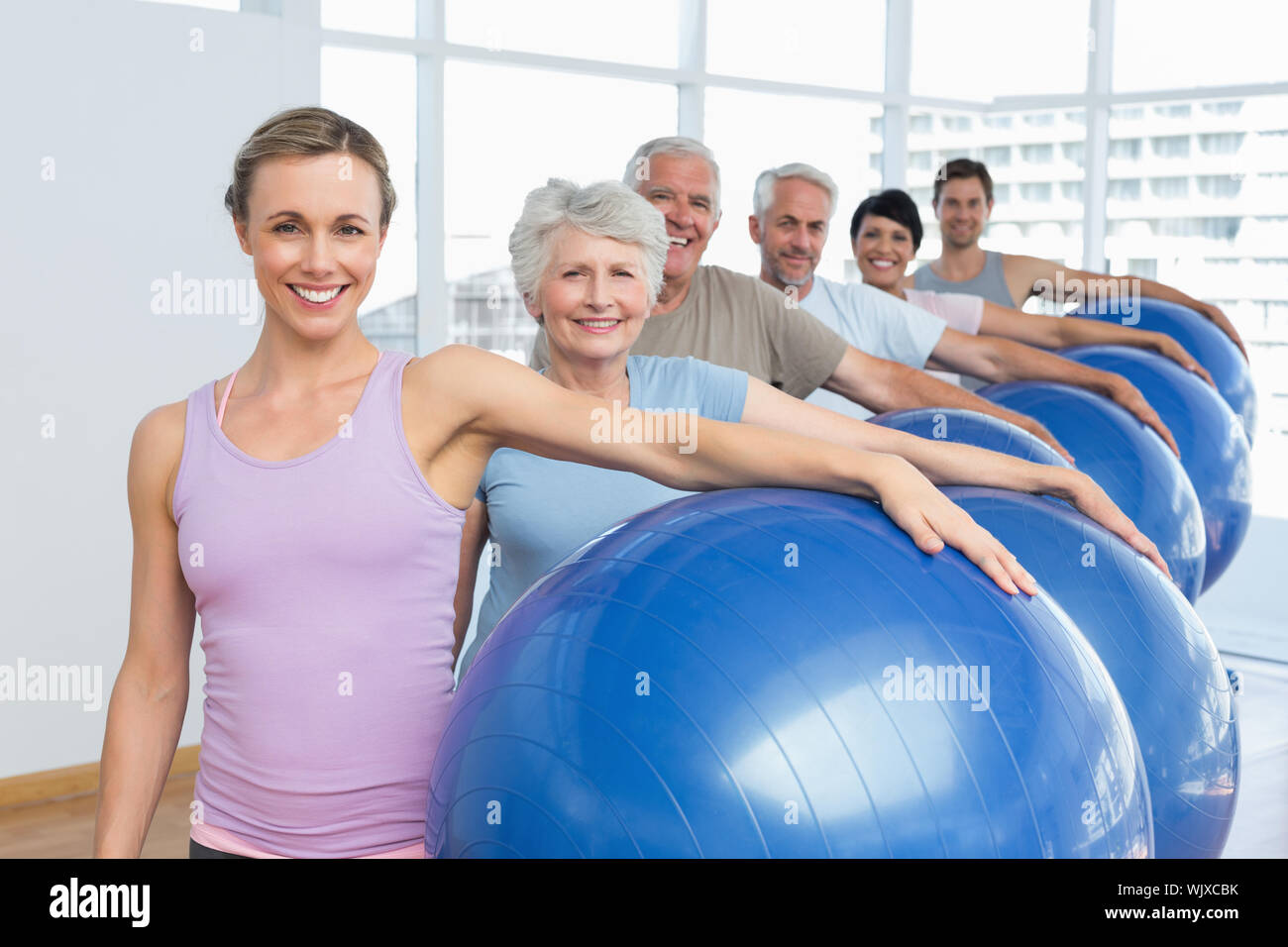 Portrait of sporty people carrying exercise balls in a row at bright ...