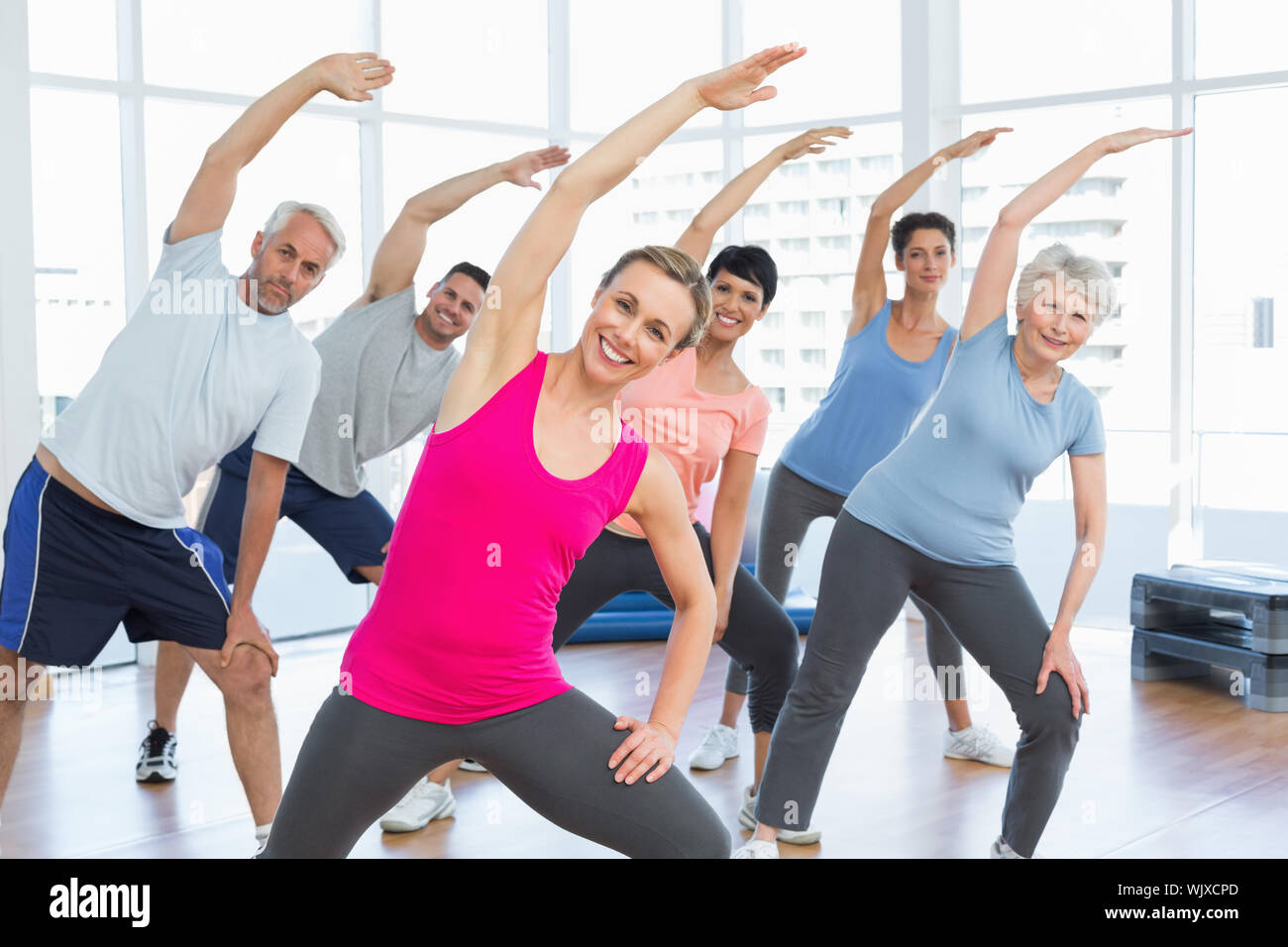 Happy female trainer with class stretching hands at yoga class Stock ...