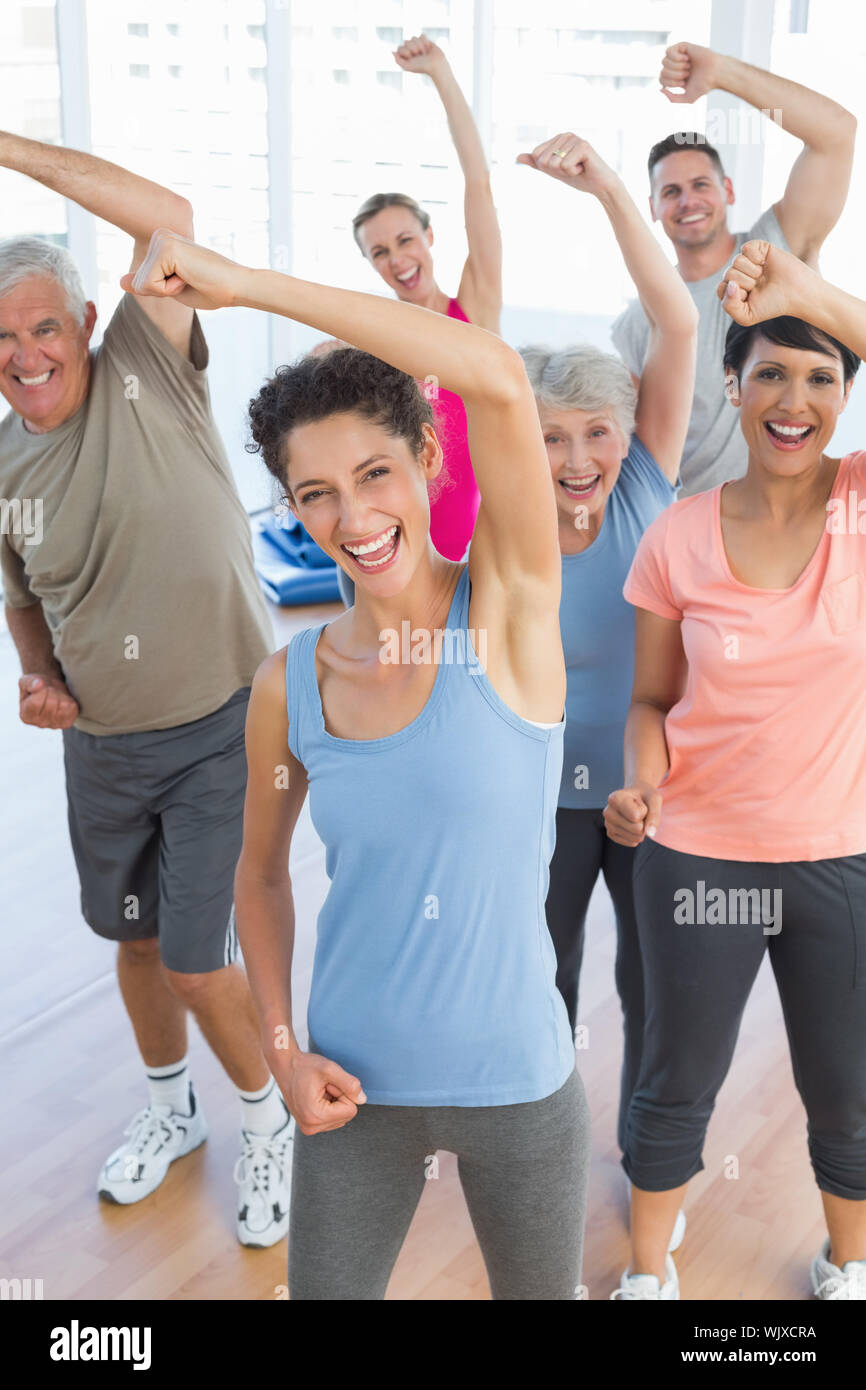 Portrait of smiling people doing power fitness exercise at yoga class ...