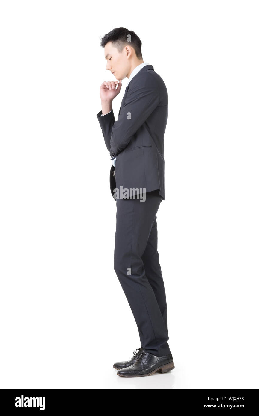 Confused young business man standing and thinking, full length portrait ...