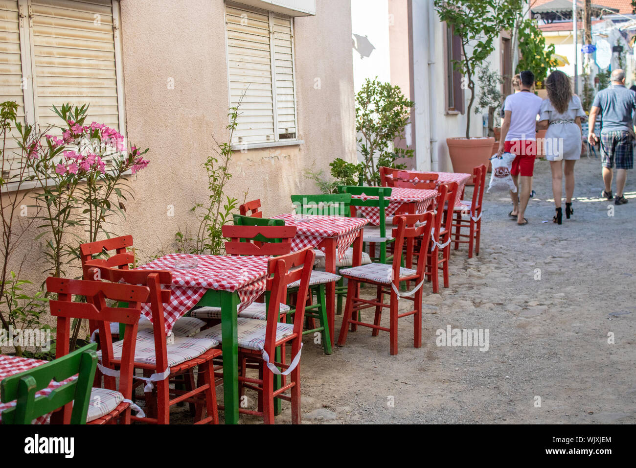 Cafe tables and chairs in the street. People walking on the street ...