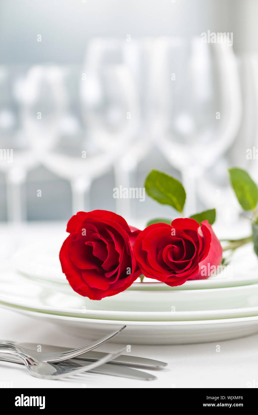 Romantic restaurant table setting for two with roses plates and cutlery ...