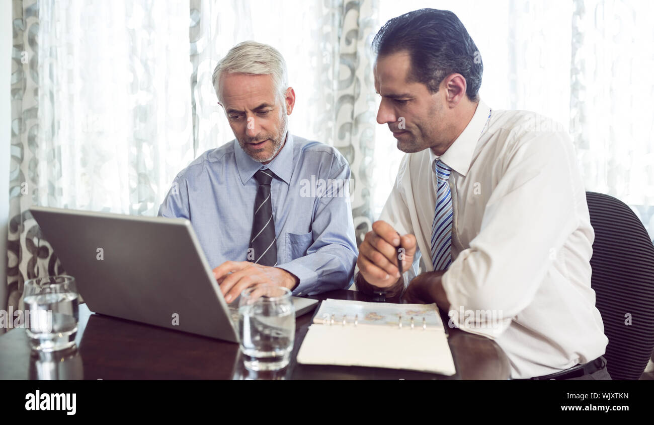 Two businessmen using laptop at desk in the office Stock Photo - Alamy