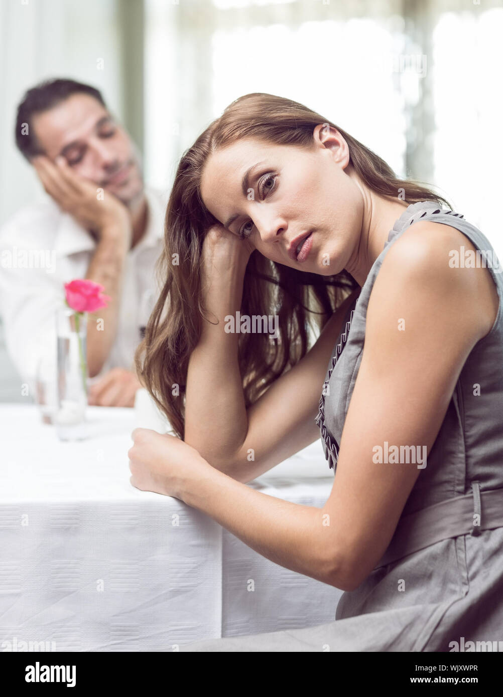 Portrait of a bored couple sitting at dining table in the restaurant ...
