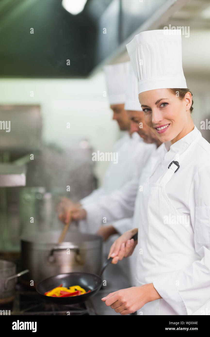 Happy chef smiling at camera while cooking at stove in a commercial ...