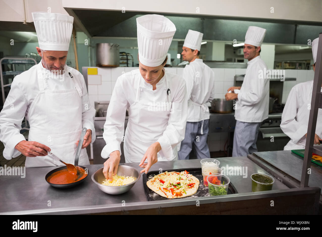 Chefs preparing a pizza together in a commercial kitchen Stock Photo ...