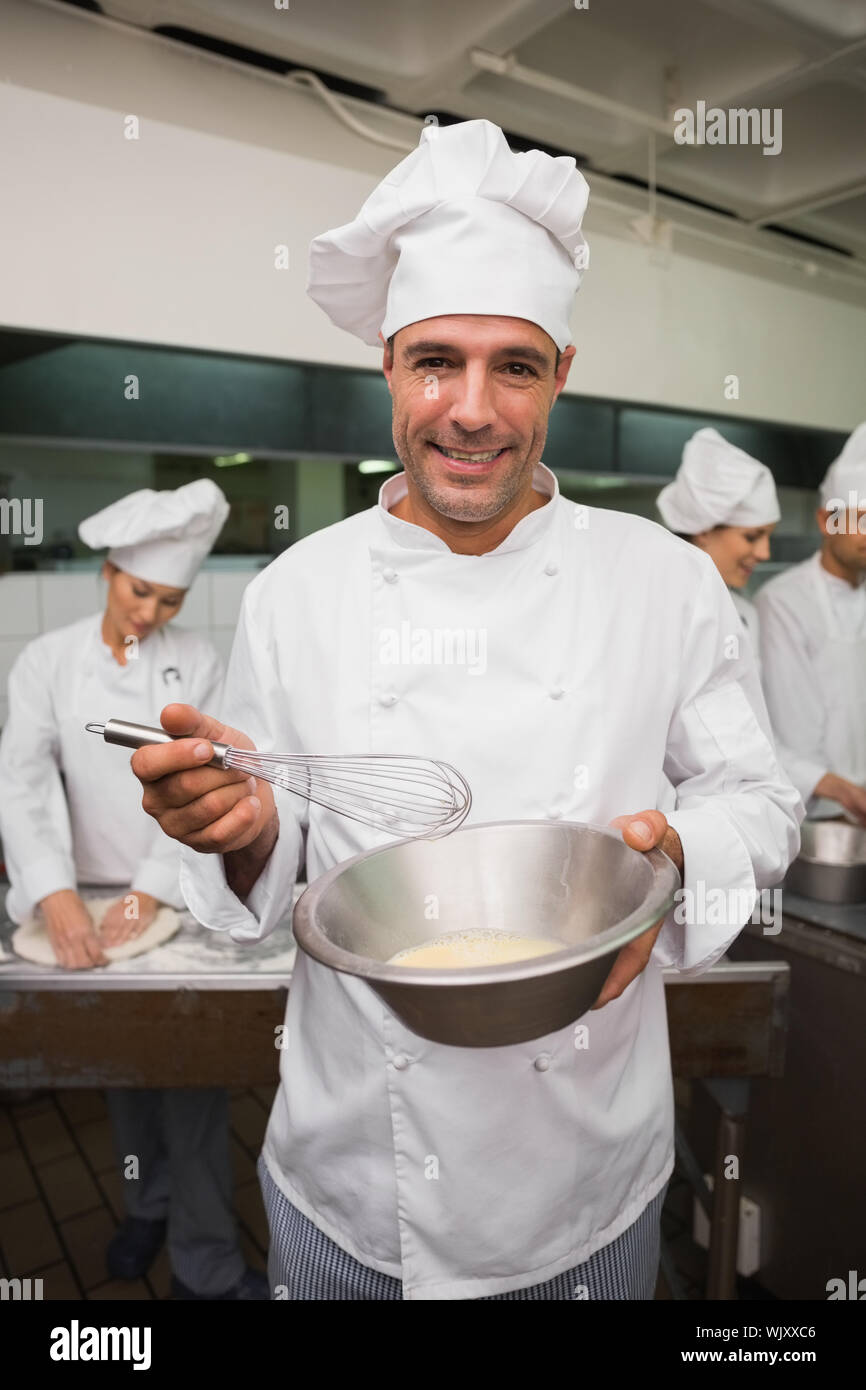 Happy chef whisking bowl of eggs smiling at camera in a commercial ...