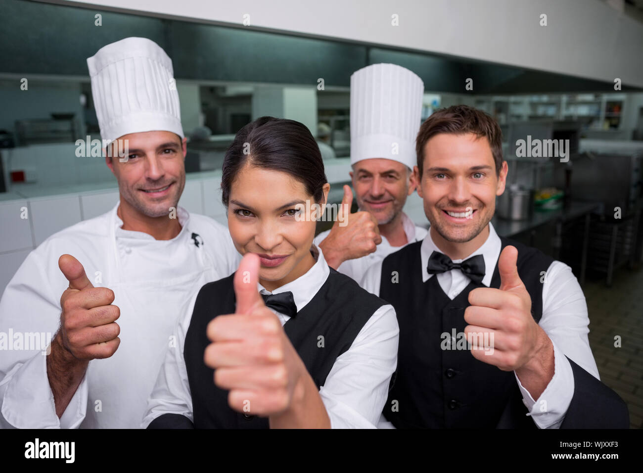 Restaurant team posing together smiling at camera giving thumbs up in a ...