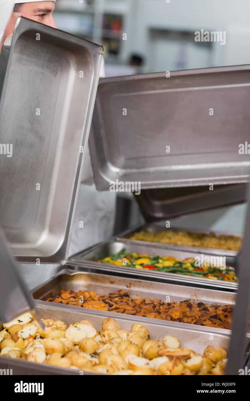 Chefs lifting lids from serving trays in a commercial kitchen Stock ...