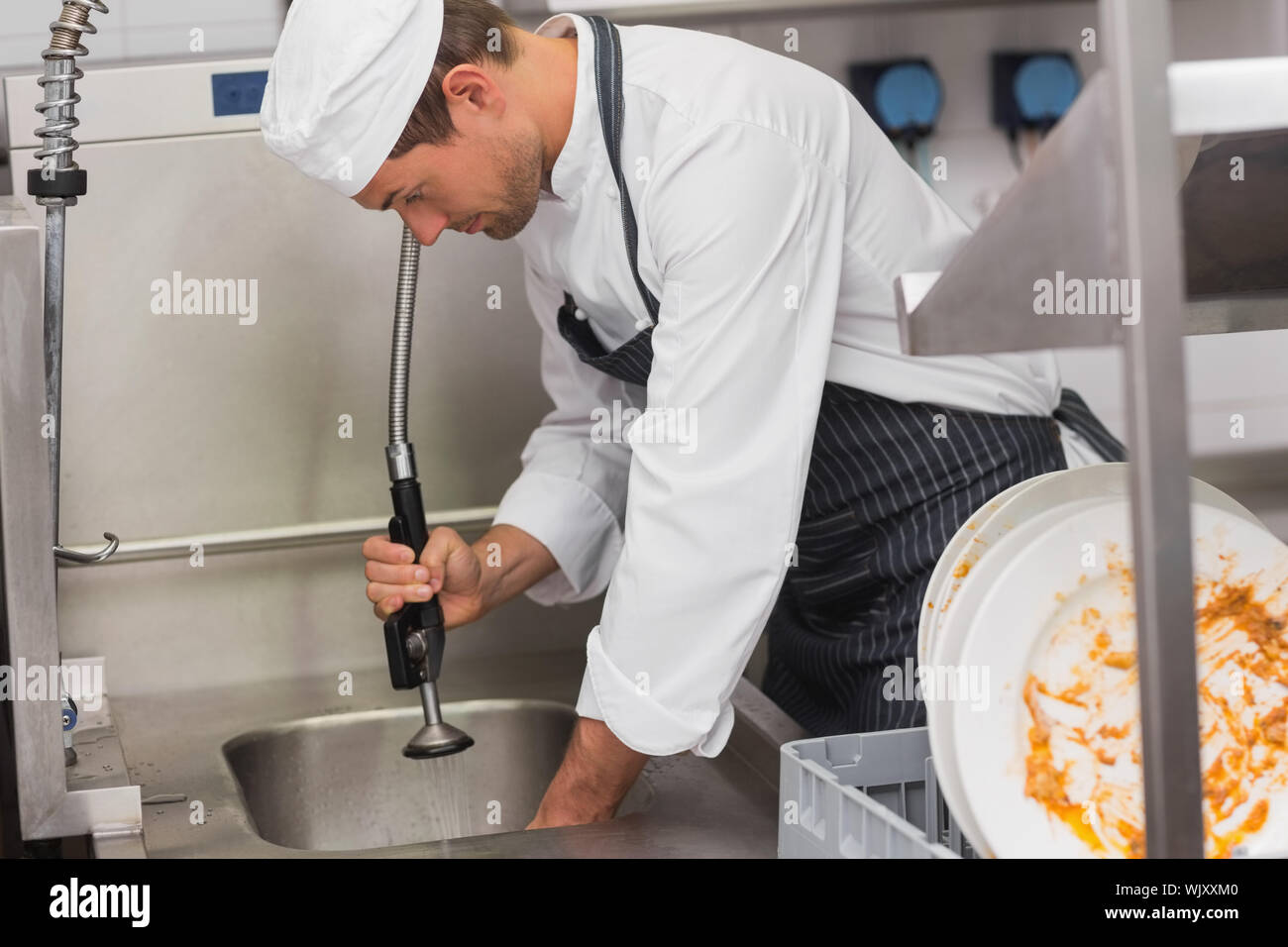 Kitchen porter cleaning plates in sink in a commercial kitchen Stock ...