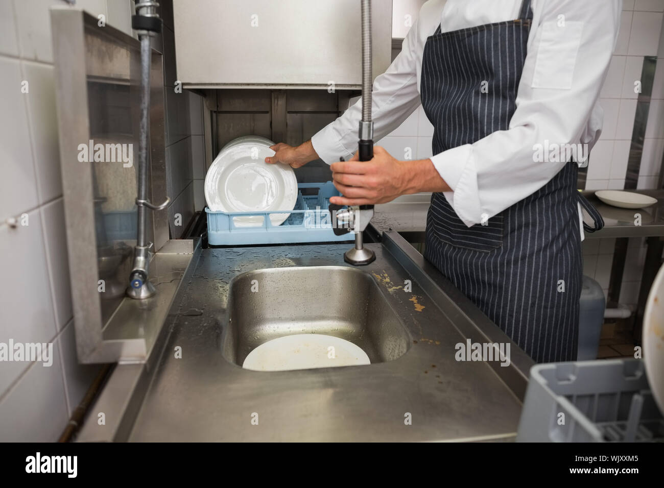 Kitchen porter cleaning plates in sink in a commercial kitchen Stock ...