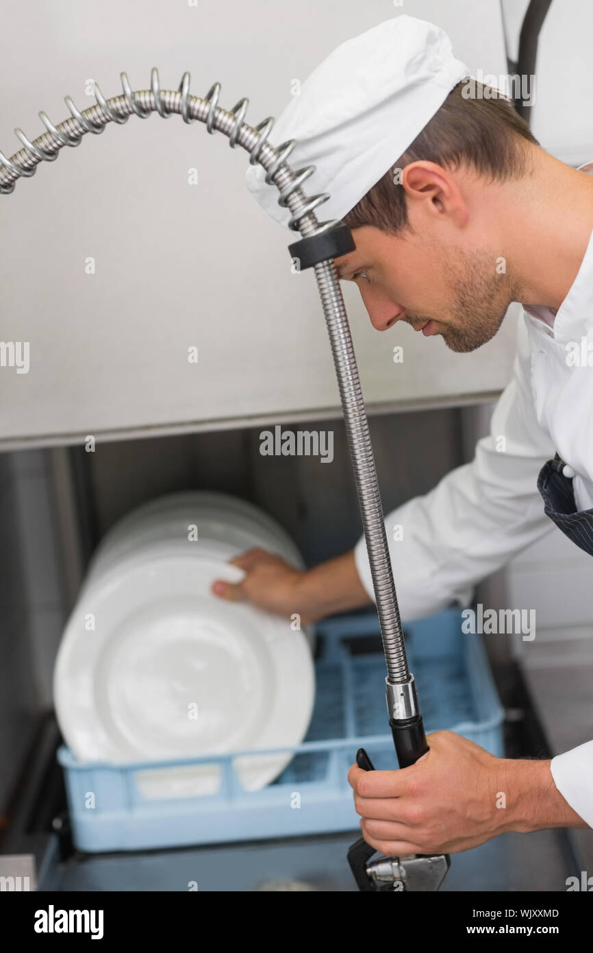 Kitchen porter cleaning plates in sink in a commercial kitchen Stock ...