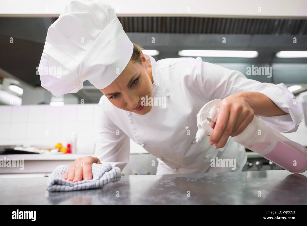Chef wiping down surface and spraying detergents in a commercial ...
